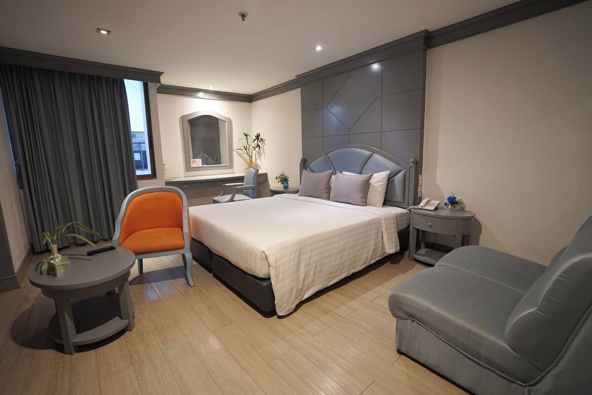 Quarto de hotel moderno com cama, sofá, escrivaninha e cadeira.