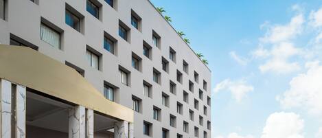 Um edifício de hotel moderno com fachada plana, várias janelas e uma placa verde.