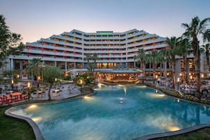 Um hotel com uma piscina grande, área de estar ao ar livre e palmeiras.