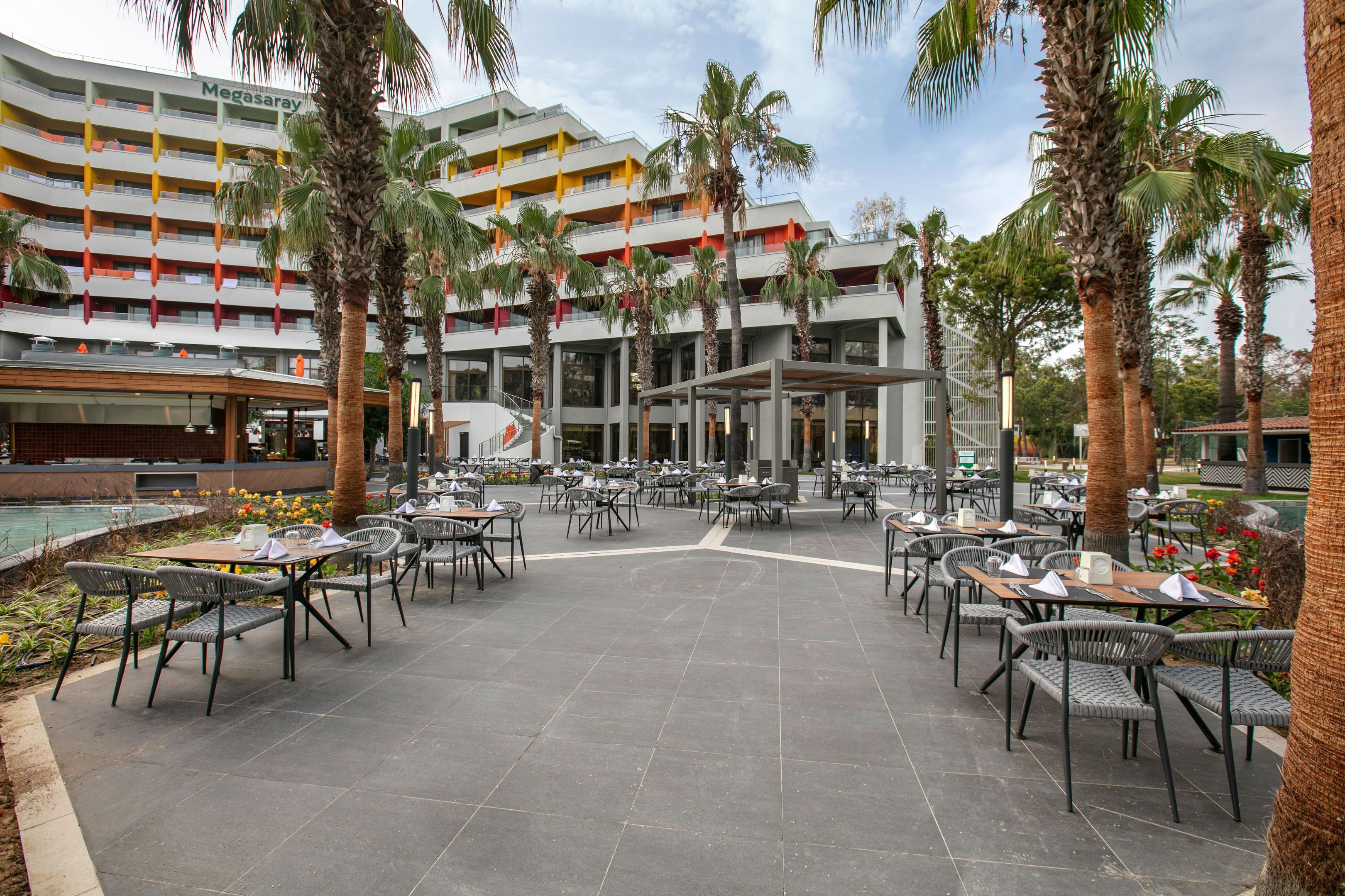 Um hotel com área de estar ao ar livre, palmeiras e piscina.