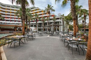 Um hotel com área de estar ao ar livre, palmeiras e piscina.