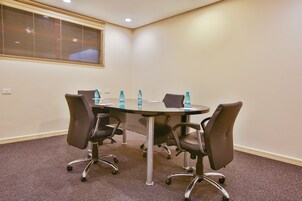 Uma sala de conferências com uma mesa redonda, quatro cadeiras e garrafas de água.