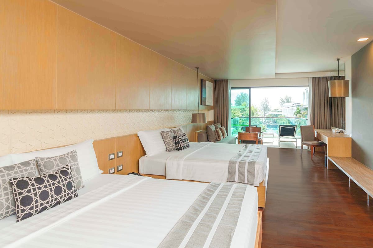 Quarto de hotel moderno com duas camas, uma escrivaninha e uma televisão.