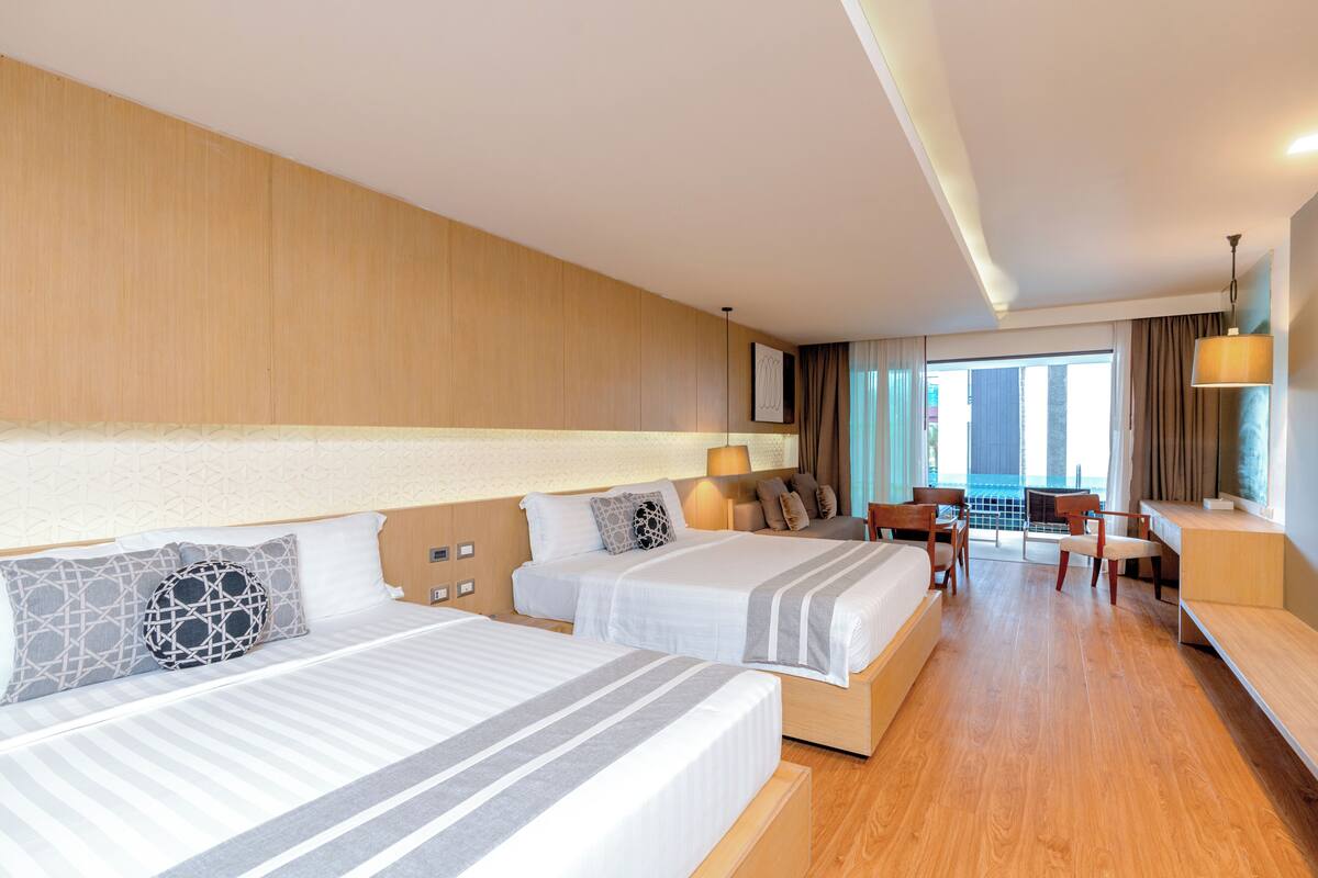 Quarto de hotel com duas camas, uma mesa e uma cadeira.