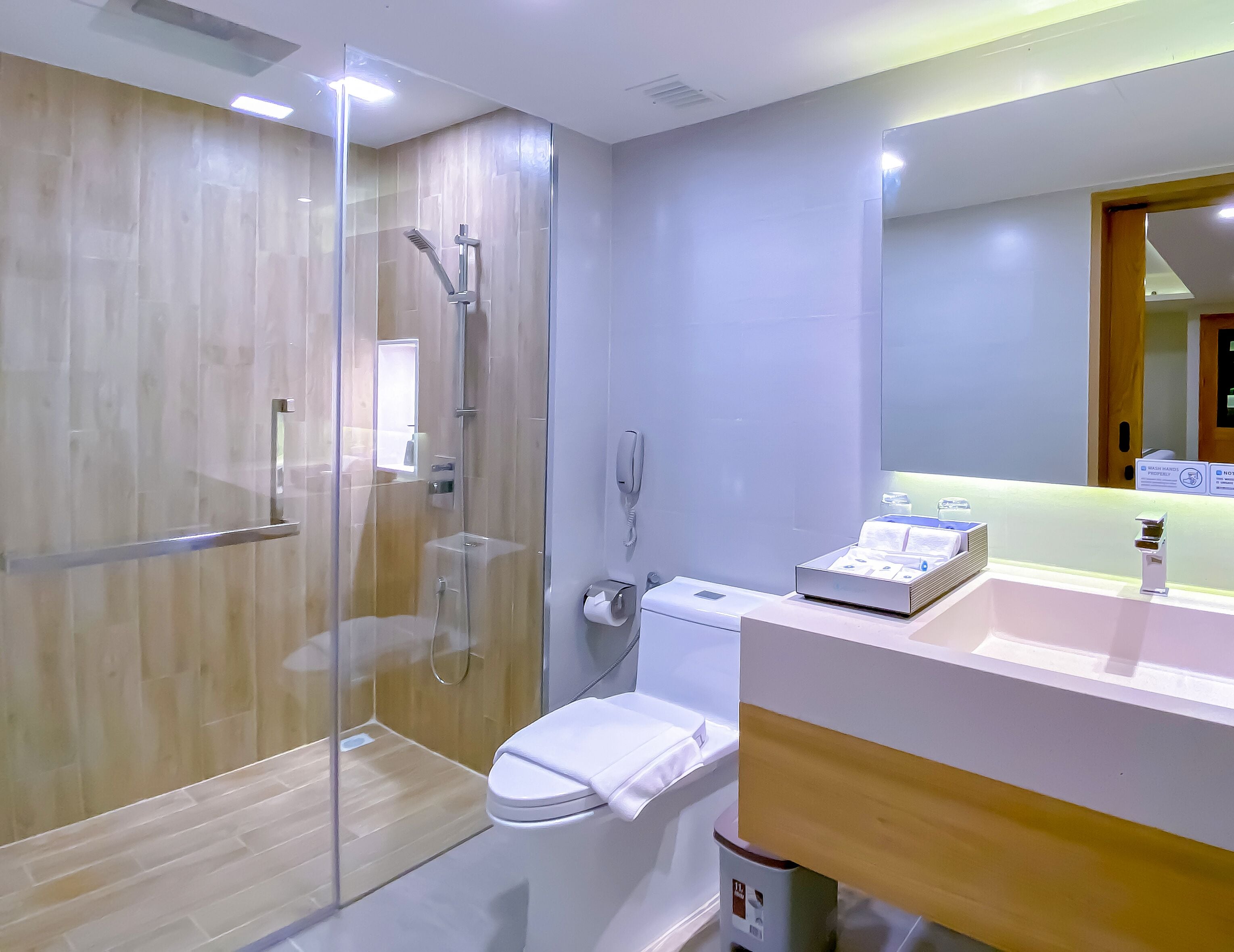 Uma casa de banho moderna com cabine de duche em vidro, sanita e lavatório com espelho em cima.