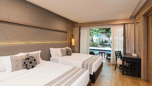 Quarto de hotel com duas camas, uma escrivaninha e vista para uma piscina.