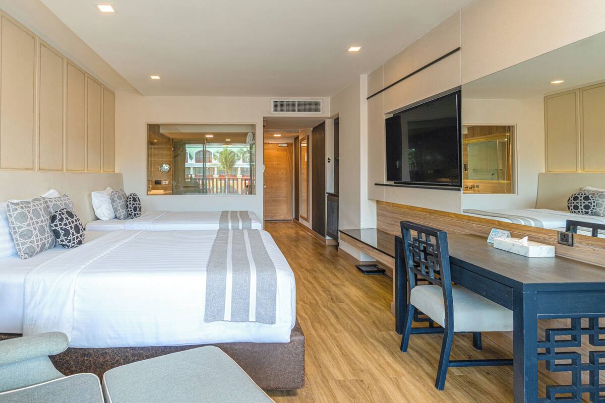 Quarto de hotel moderno com duas camas, uma escrivaninha e uma televisão.