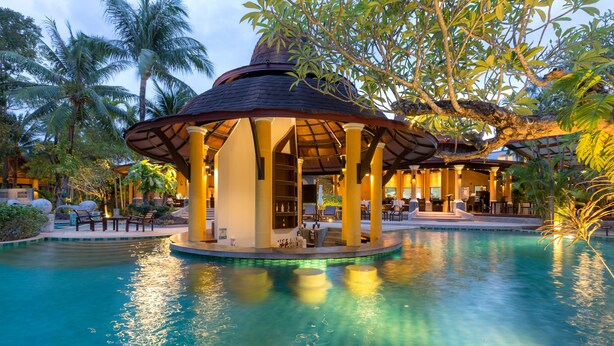 Uma área de piscina com um gazebo, palmeiras e cadeiras de descanso.
