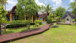 Resort com deck de madeira, vegetação exuberante e arquitetura tradicional.