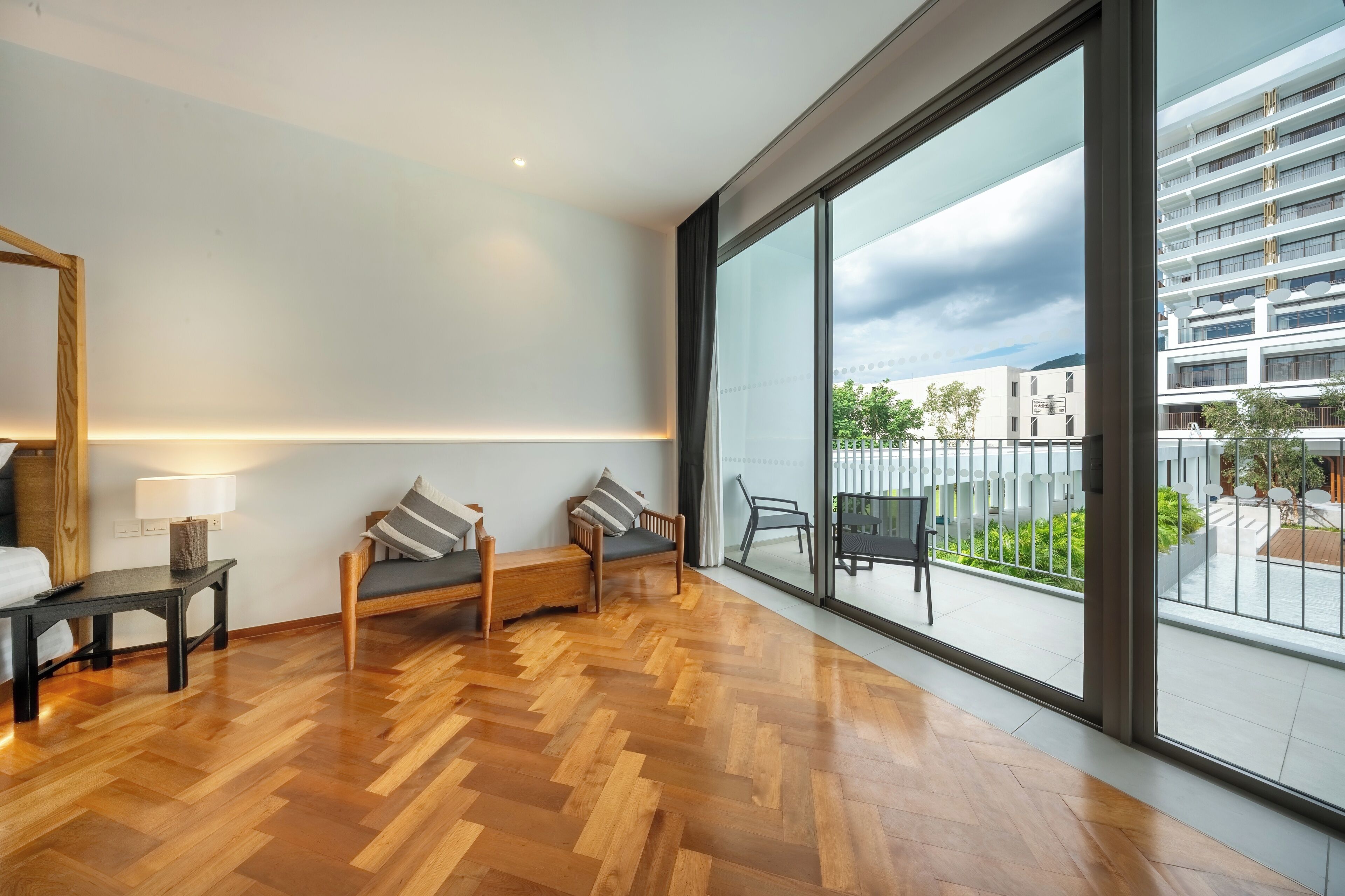 Quarto de hotel moderno com varanda ampla, piso de madeira e vista para a cidade.