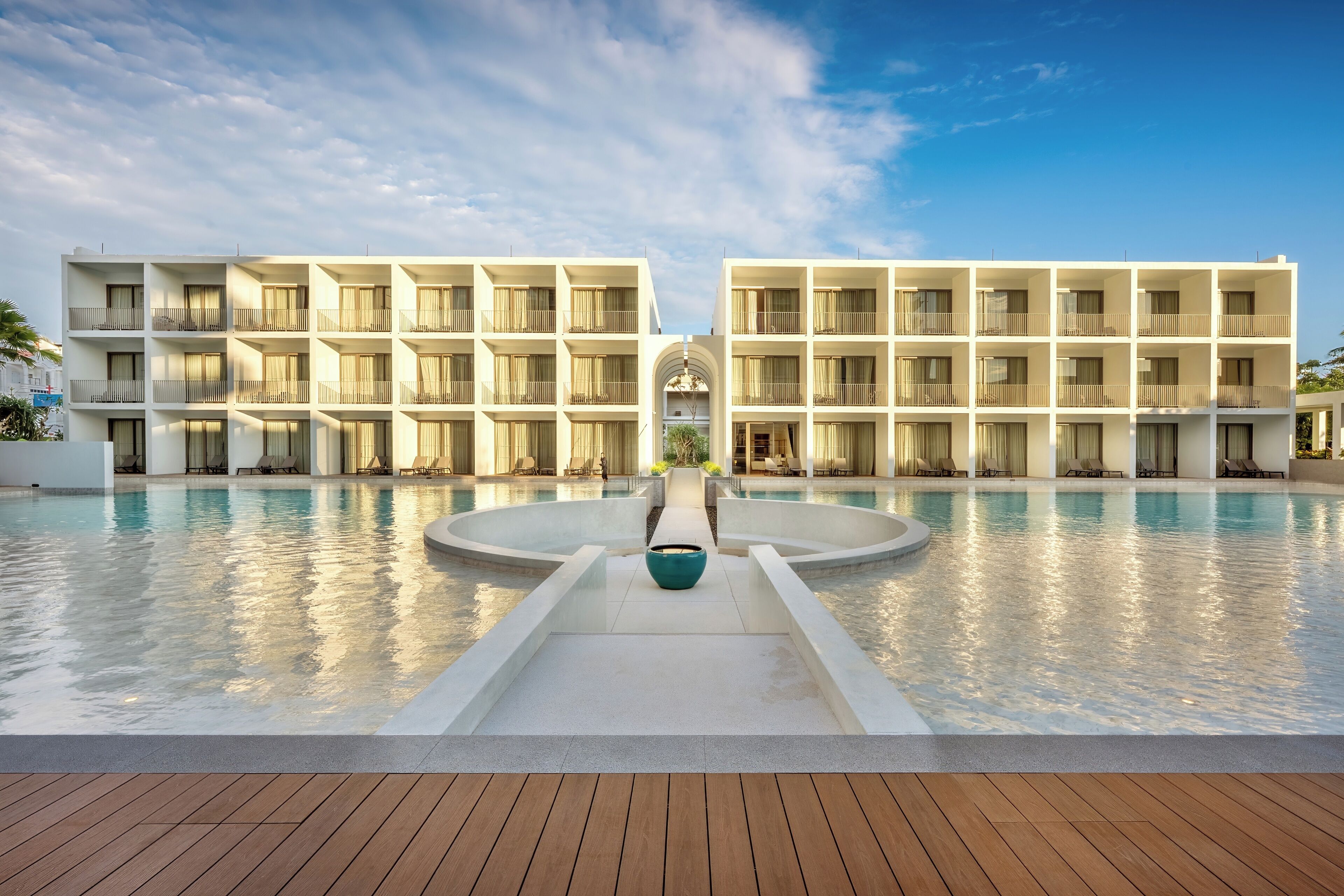 Um hotel com piscina, várias varandas e uma fonte central.
