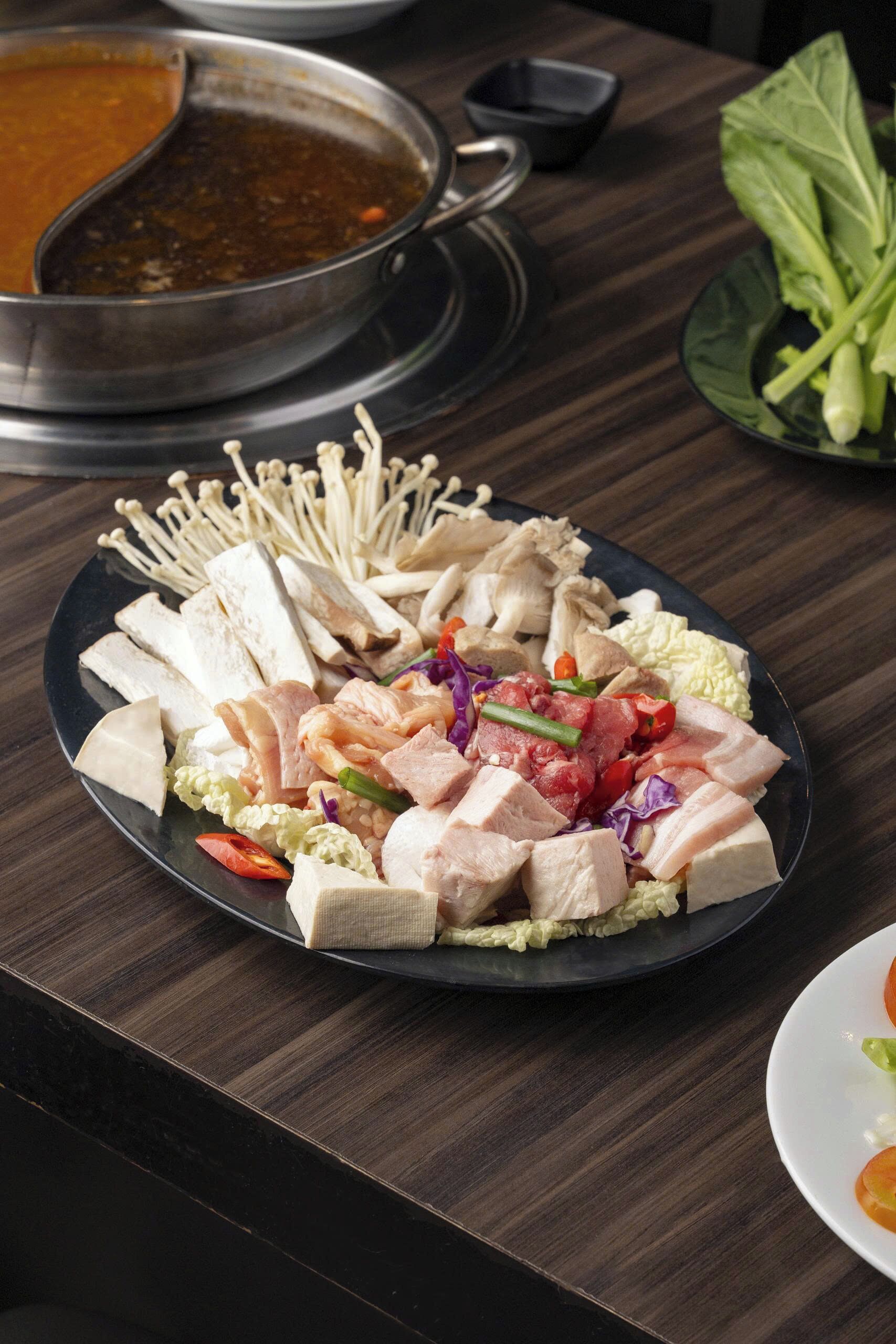 Um prato com fatias de carne, legumes e cogumelos sobre uma mesa.