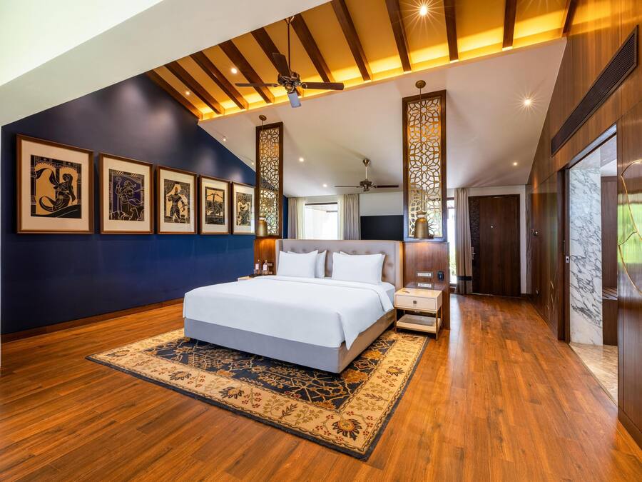 Quarto moderno com cama grande, piso de madeira e ventoinha no teto.
