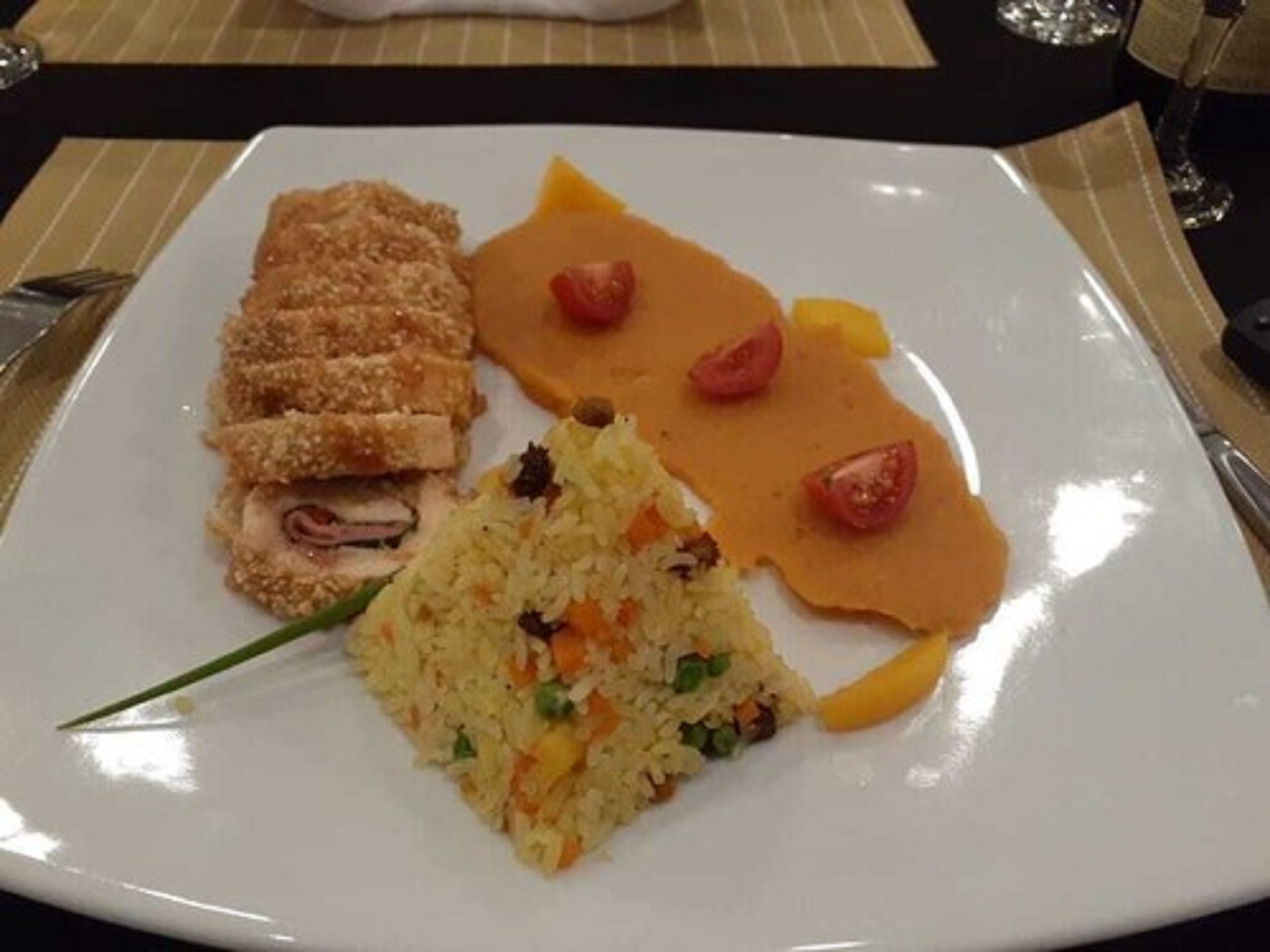 Um prato com escalope à milanesa, arroz com legumes e uma fatia de abóbora.
