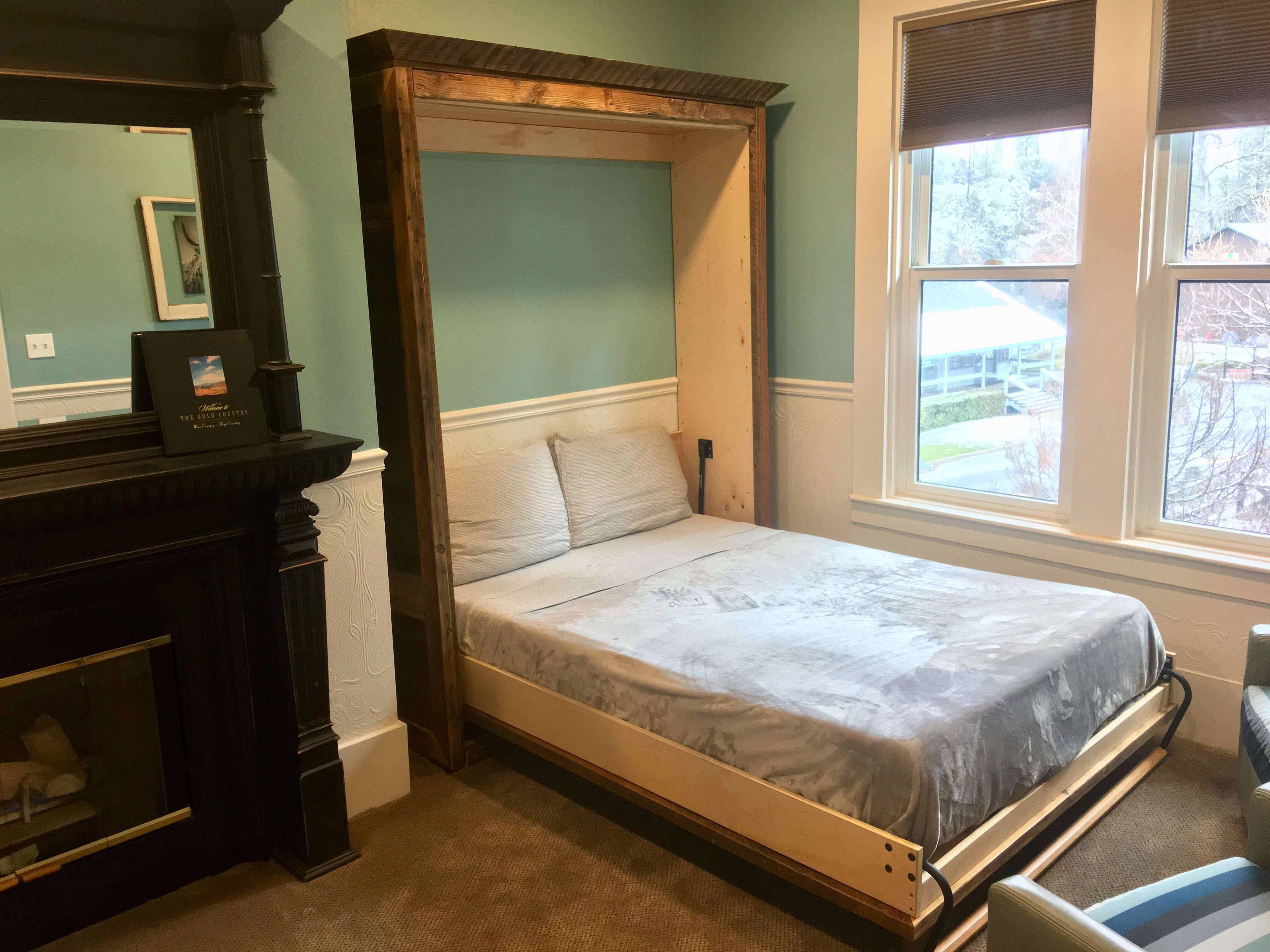 Quarto com uma cama de madeira com dossel, cômoda e janela com vista para o exterior.
