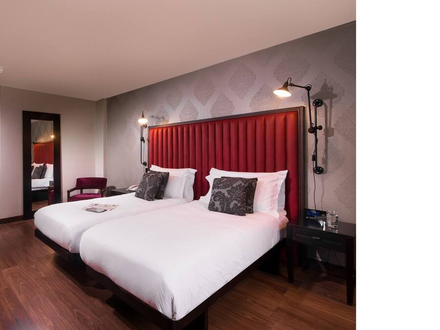 Quarto de hotel com duas camas, uma escrivaninha e uma cadeira.