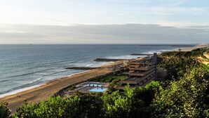 Um resort à beira-mar com piscina na orla, vista para o oceano e uma praia de areia.