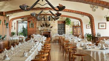 Um restaurante com arcos de tijolo, toalhas de mesa brancas e cadeiras de madeira.