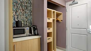 Uma cozinha compacta com micro-ondas, cafeteira e armário com painel de mármore.