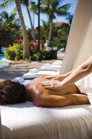 Uma pessoa recebendo massagem nas costas em uma mesa de massagem, perto de uma piscina.