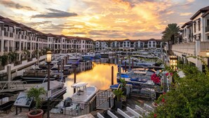 Marina com barcos atracados, um canal e edifícios com varandas e guarda-corpos.