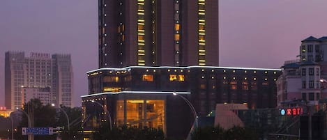 Um hotel alto com vários andares, um 'R' bem visível na lateral e fachada bem iluminada.