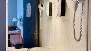 Casa de banho com lavatório, espelho e secador de cabelo fixado na parede.