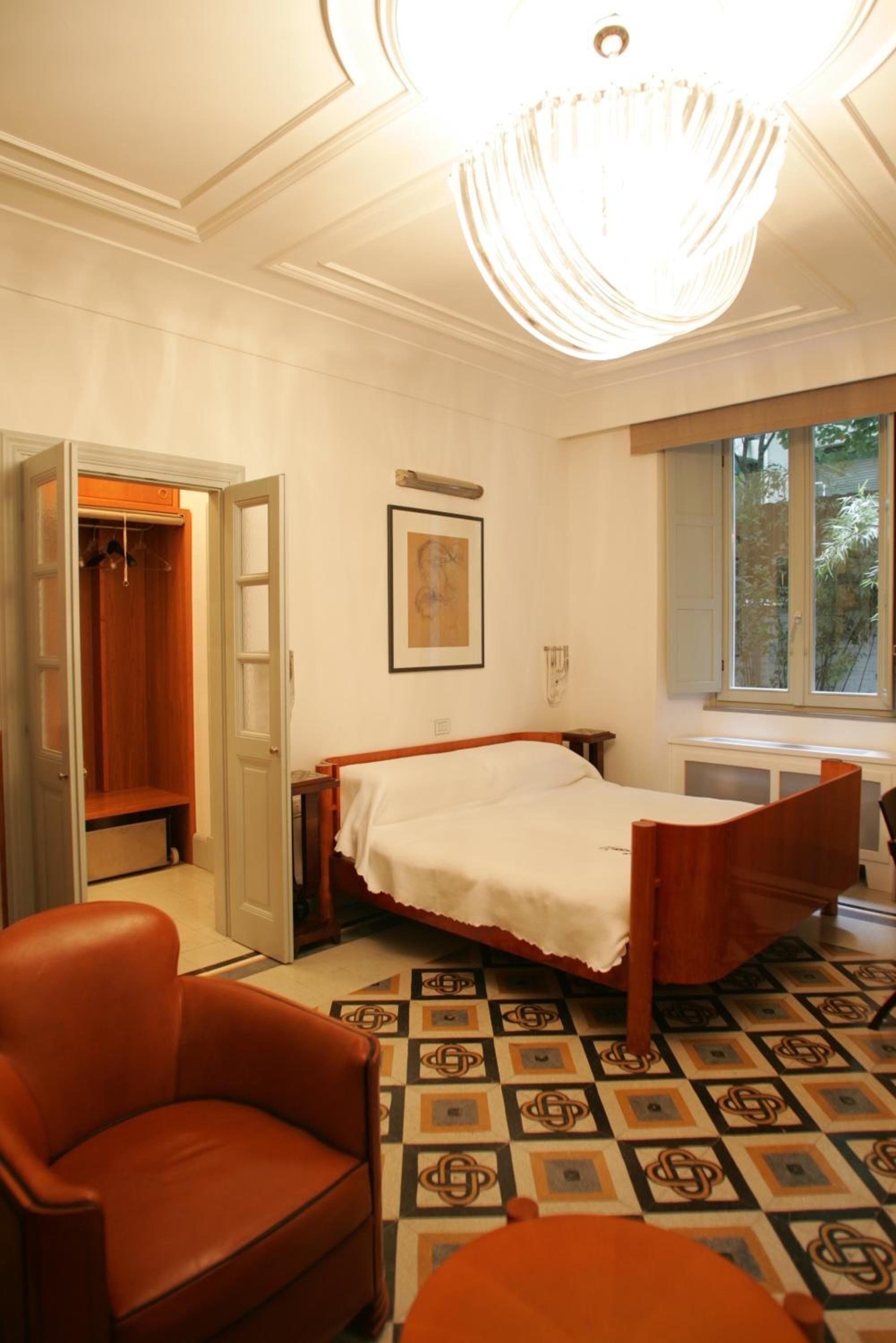 Quarto com cama, cadeira, guarda-roupa e janela.
