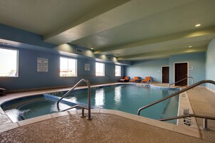 Piscina interna com água cristalina, plataforma de mergulho e espreguiçadeiras.