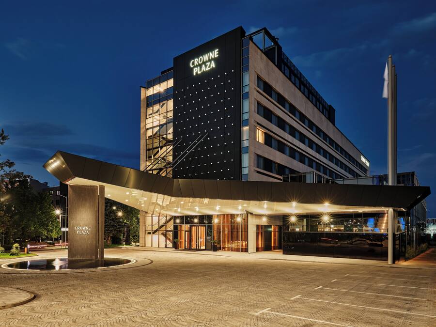 Uma entrada de hotel moderna com uma placa de destaque que diz "Crowne Plaza".