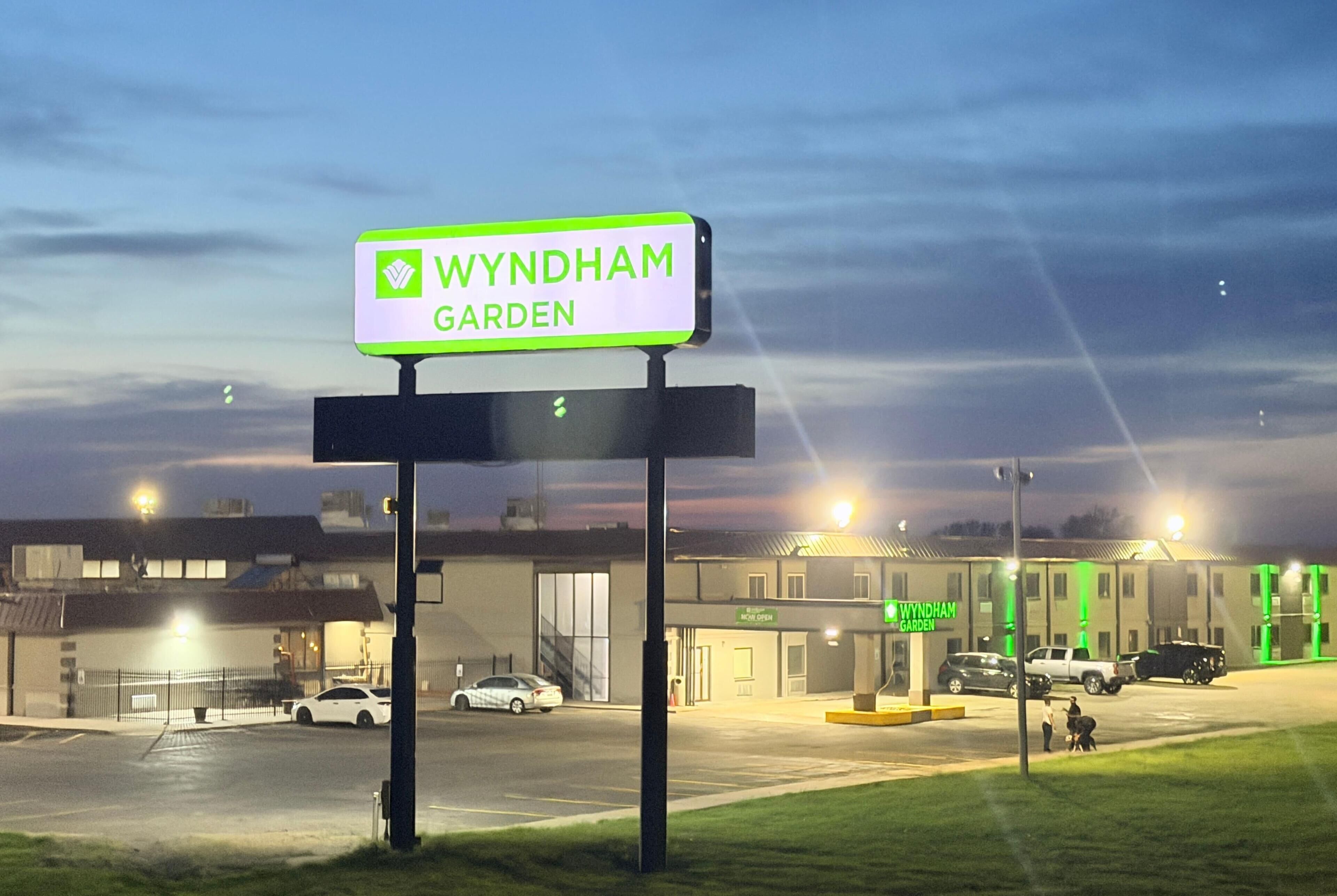 Placa do hotel Wyndham Garden, com um estacionamento e edifícios ao fundo.