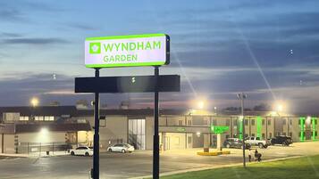 Placa do hotel Wyndham Garden, com um estacionamento e edifícios ao fundo.