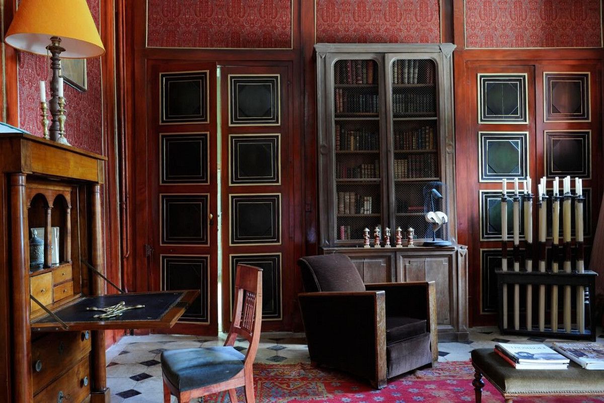 Um quarto com uma escrivaninha de madeira, uma cadeira, uma estante e um piano.
