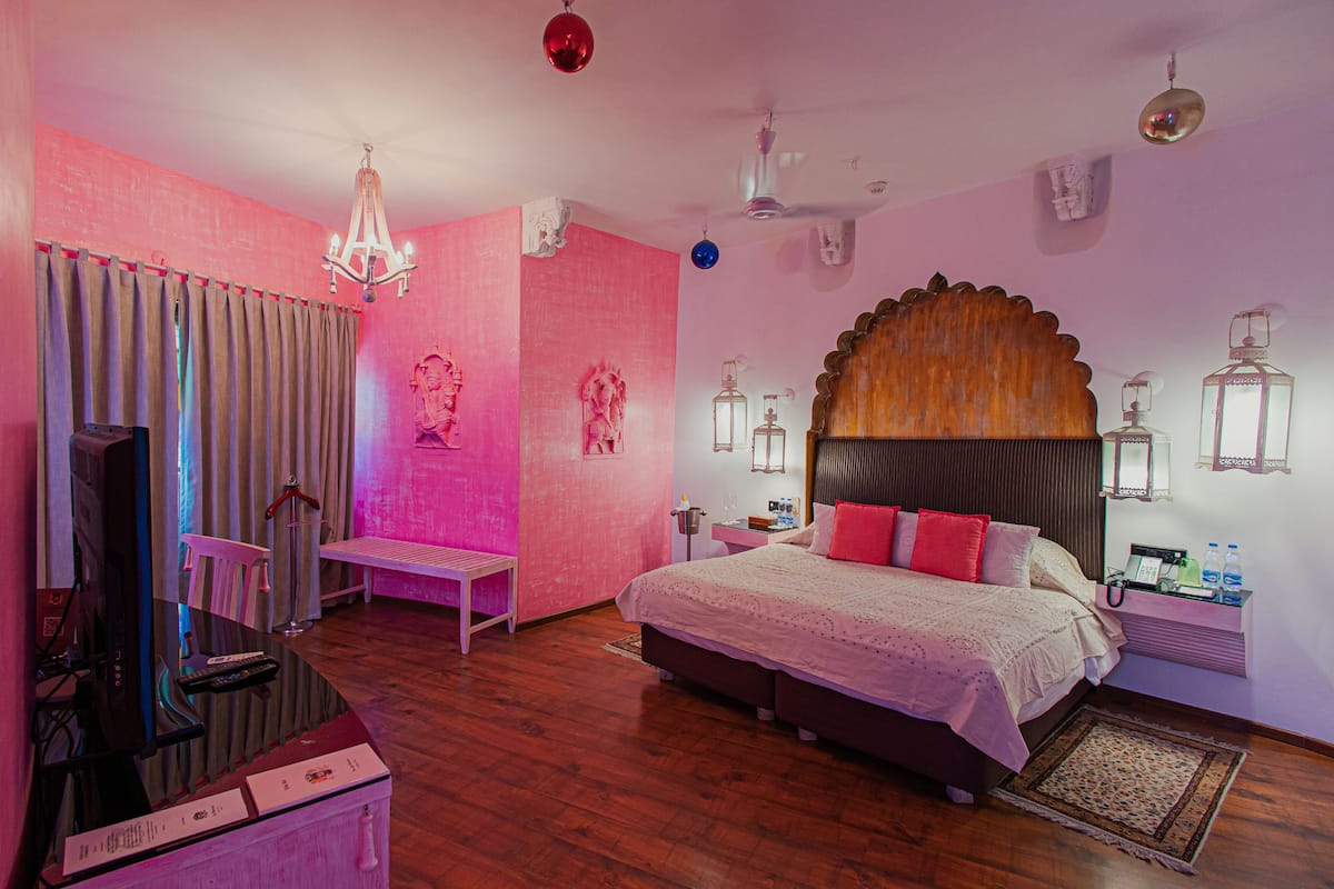 Quarto com uma cama grande, uma escrivaninha, uma cadeira e uma televisão.