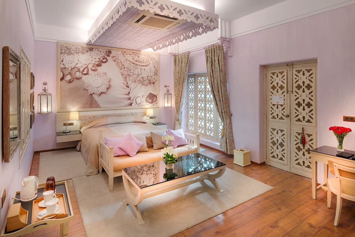 Quarto com cama, mesas de cabeceira, mesa de centro de vidro, escrivaninha e uma cadeira.