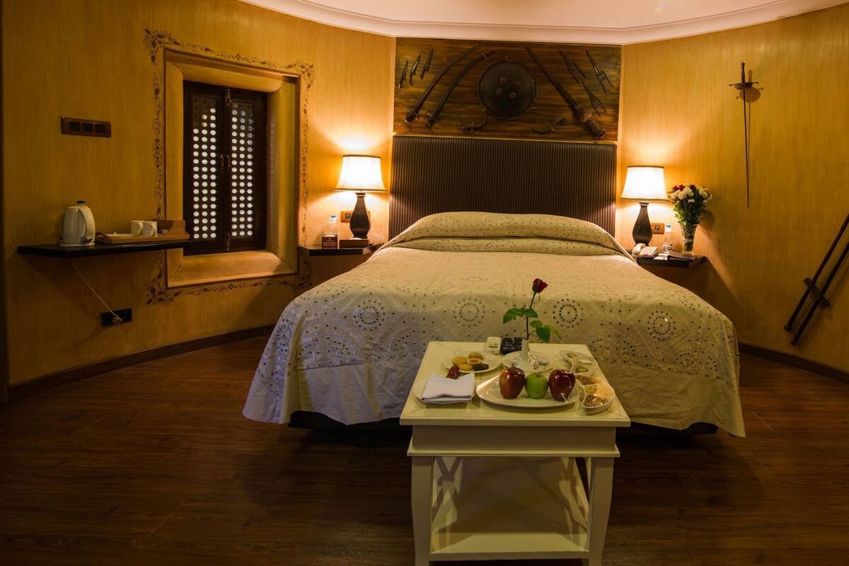 Quarto com cama, mesa de café da manhã e janela com vista.