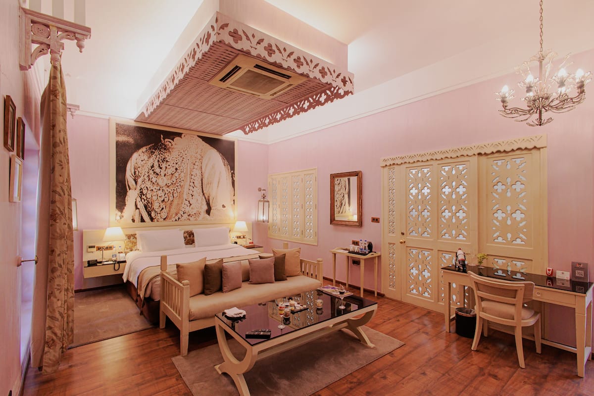 Um quarto com cama, sofá, escrivaninha e mesa de centro.