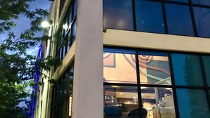 Um edifício moderno com grandes janelas e espaço interior visível, com assentos e mesas.