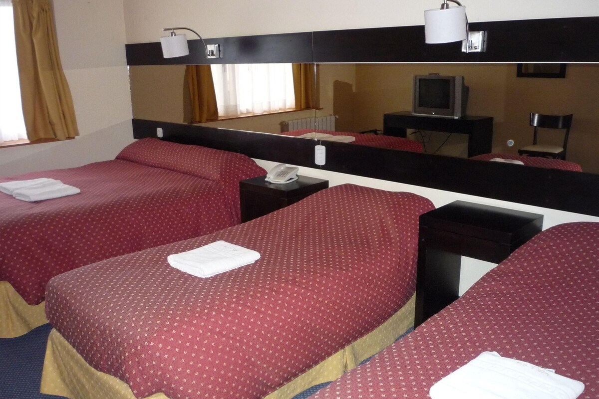 Quarto de hotel com duas camas, televisão, espelho e telefone.