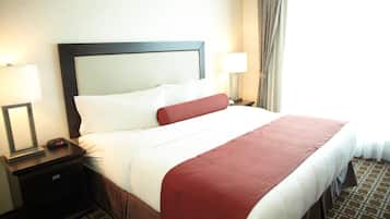 Quarto de hotel com cama grande, duas mesas de cabeceira e uma luminária.