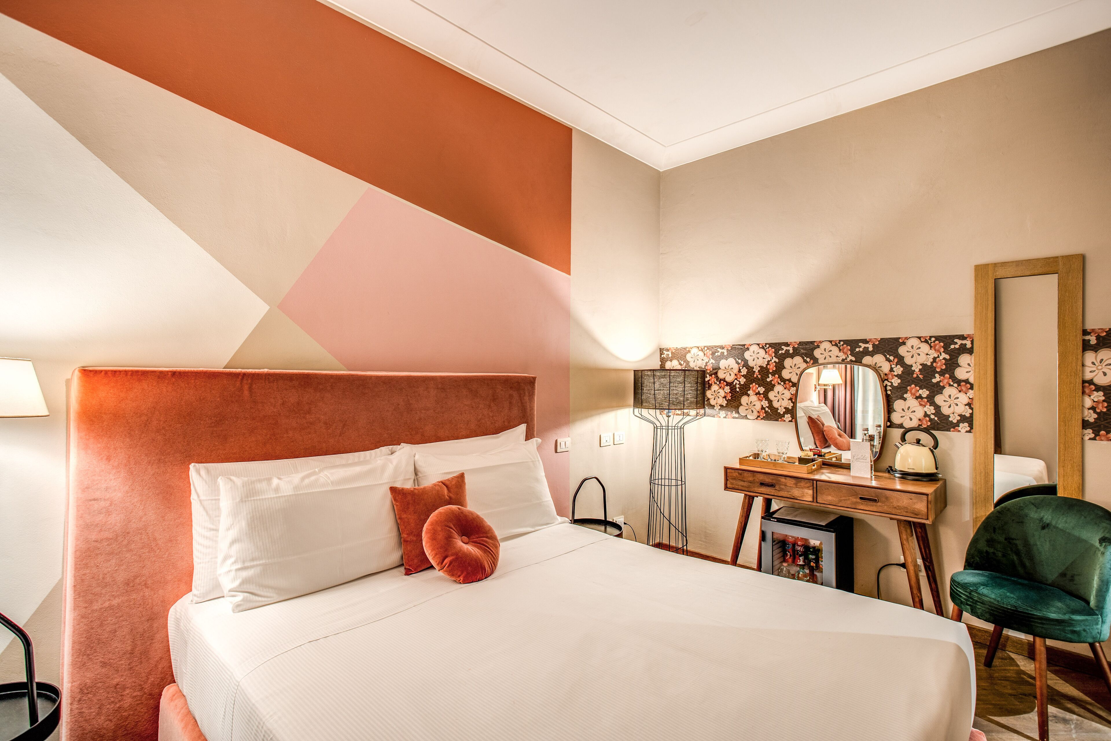 Quarto de hotel com uma cama grande, uma escrivaninha, uma cadeira e um espelho.