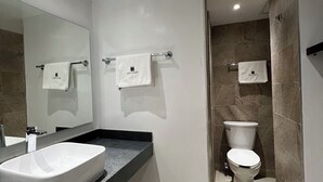 Casa de banho moderna com uma grande pia, sanita e espelho.