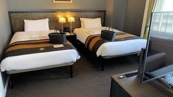 Quarto de hotel com duas camas, uma televisão e uma mesa de cabeceira.
