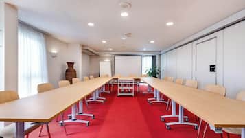 Uma sala de conferências com uma mesa comprida, cadeiras e um tapete vermelho.