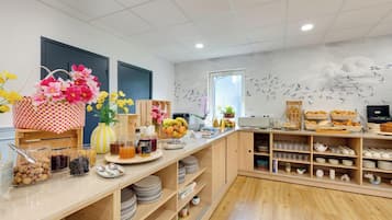 Um buffet de café da manhã com diversos alimentos e um painel decorativo na parede.