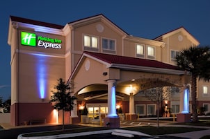 Edifício Holiday Inn Express com design moderno, destacando uma entrada imponente com varanda coberta e fachada bem iluminada.