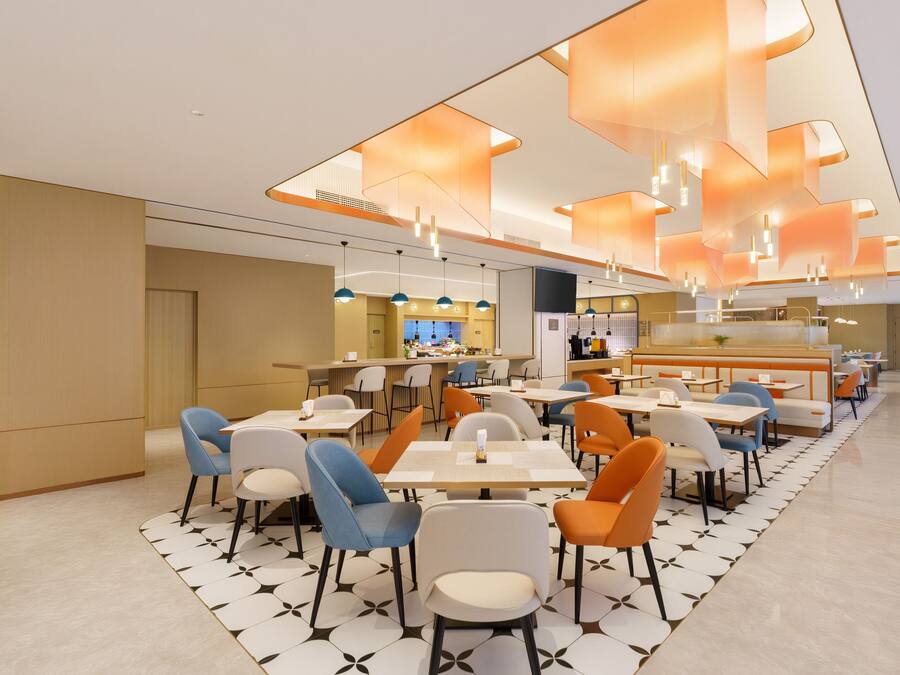 Um restaurante moderno com um balcão extenso, várias áreas de estar e iluminação pendente.