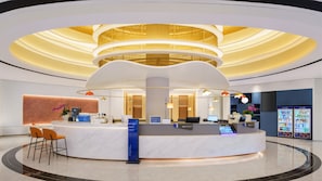 Um lobby de hotel moderno com uma recepção central, área de estar e um design circular grande no teto.