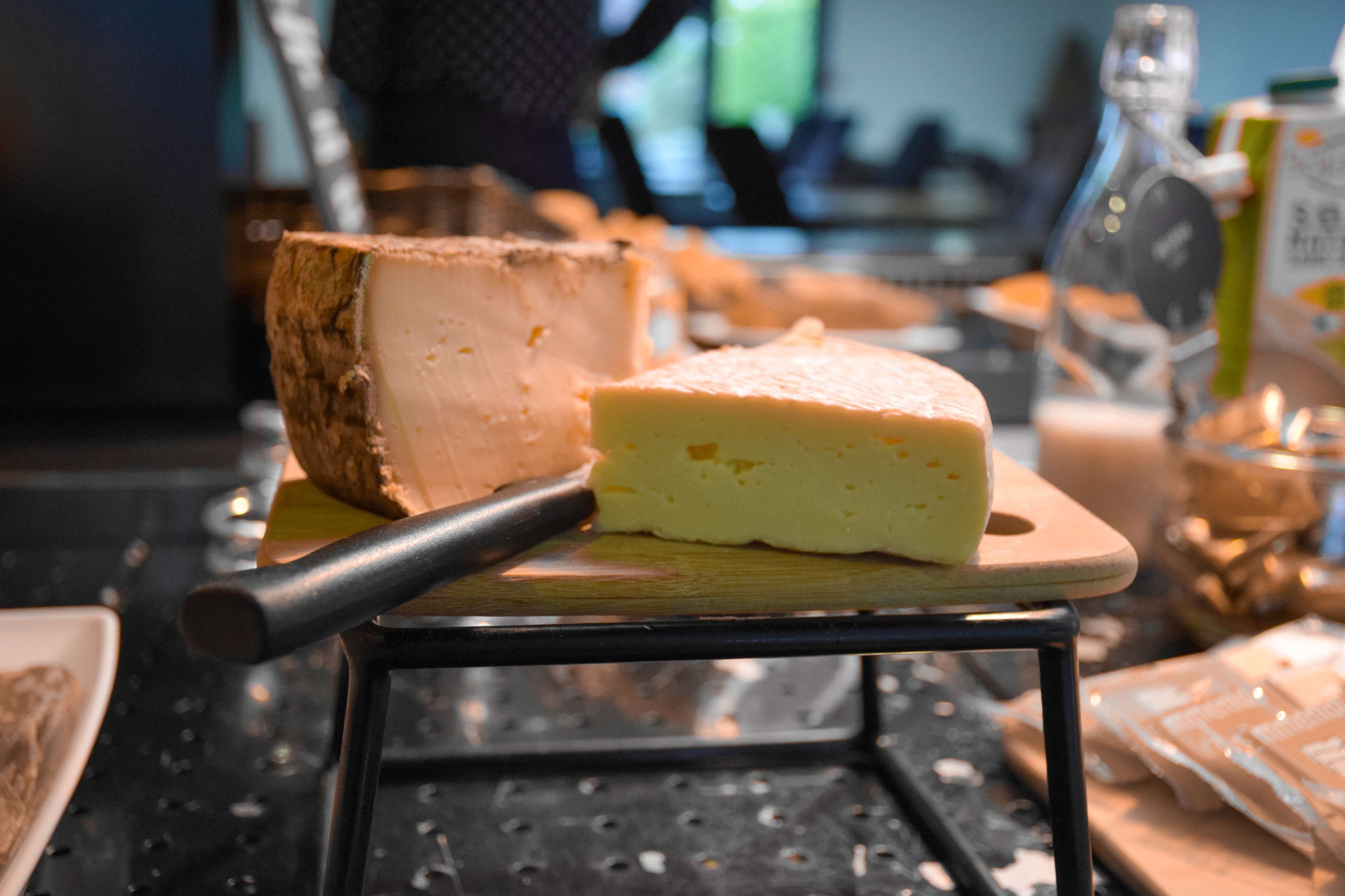 Um queijo redondo sobre uma tábua de madeira, com uma faca de queijo ao lado.