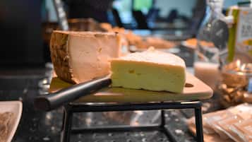 Um queijo redondo sobre uma tábua de madeira, com uma faca de queijo ao lado.